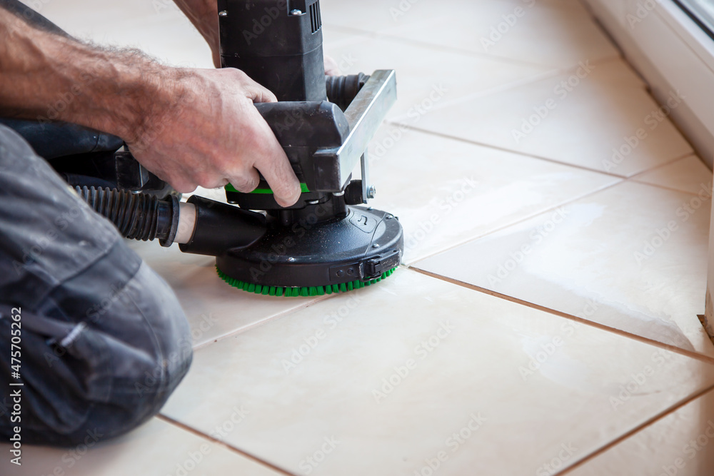 Man is working with a Grinder. Tiles floor surface grinding by electric ...