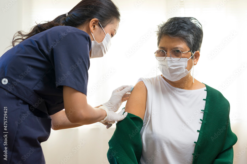 Nurse or doctor giving shot to senior female patient. Retired woman in ...
