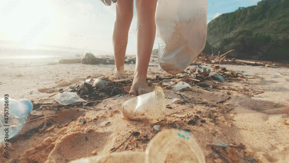 Barefoot woman collects plastic trash pollutants walks on beach putting ...