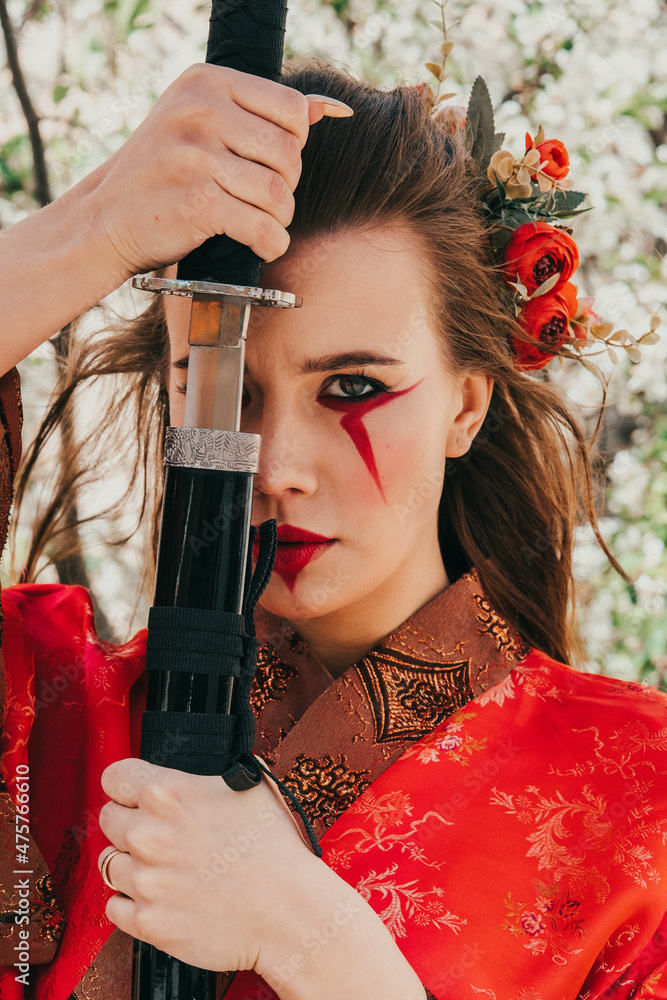 Young girl in traditional kimano in a blooming garden with samurai ...