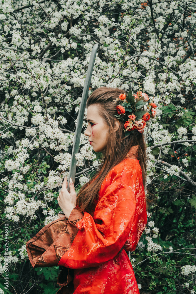 Young girl in traditional kimano in a blooming garden with samurai ...
