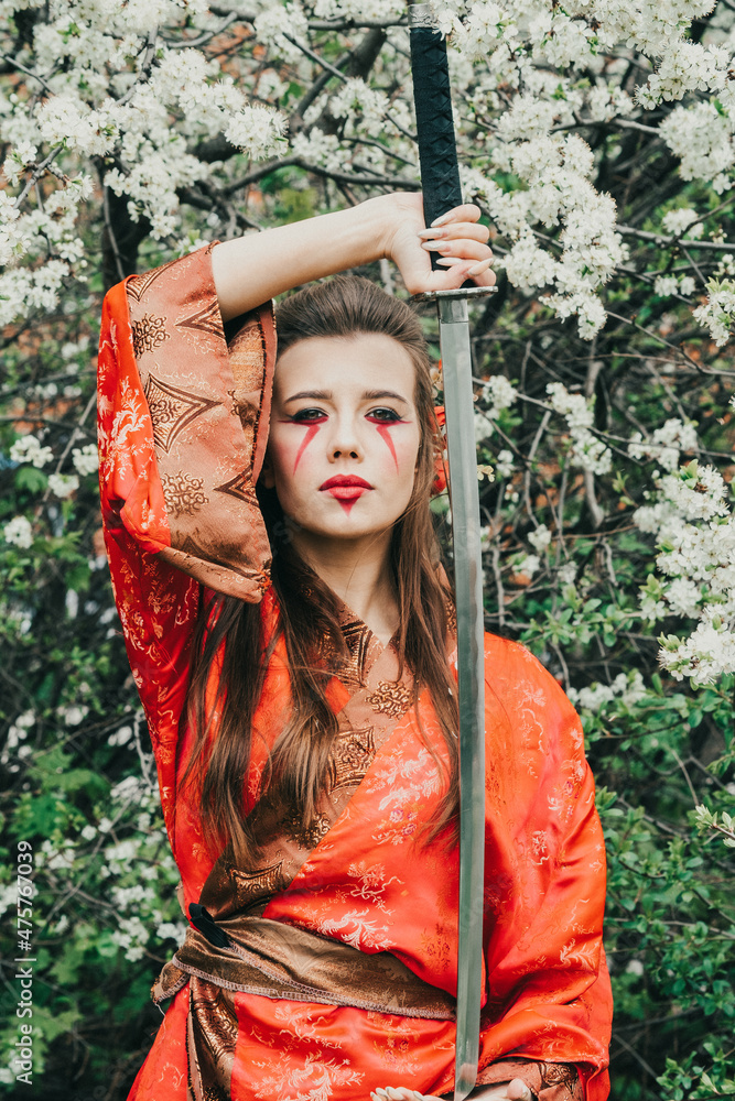 Young girl in traditional kimano in a blooming garden with samurai ...