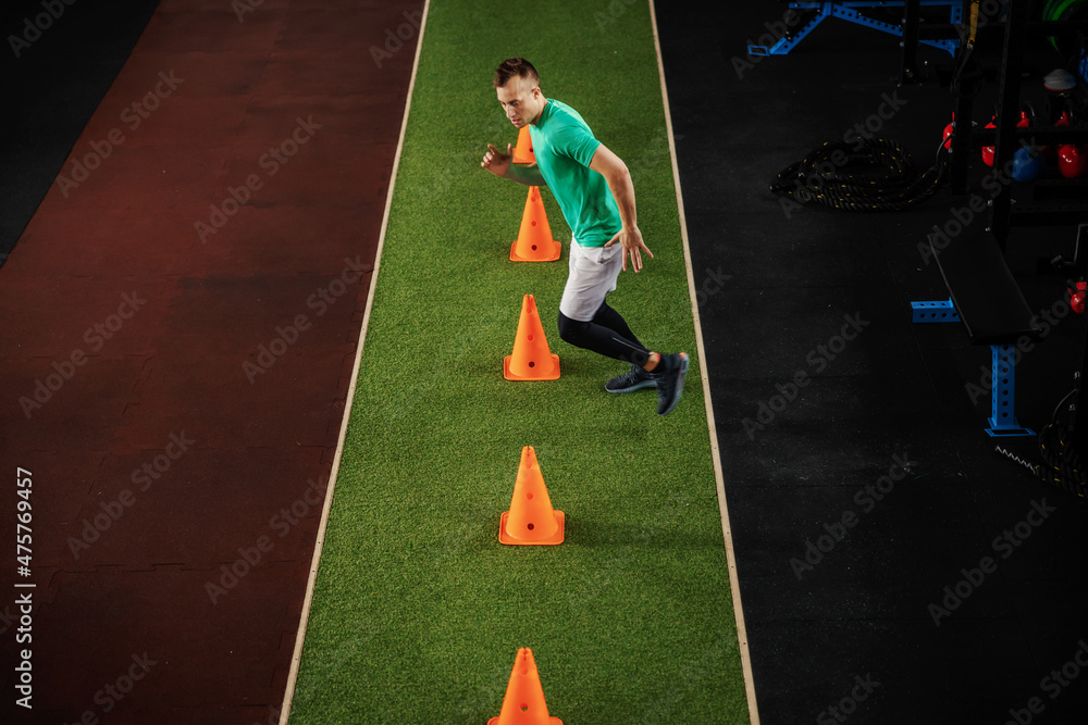 Foto de Exercises with cones. The man jumps over and runs sideways ...
