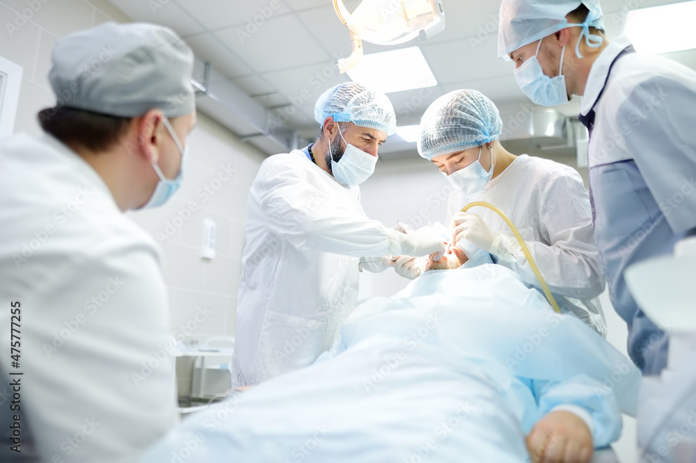 Surgeon and nurse during a dental operation. Anesthetized patient in ...