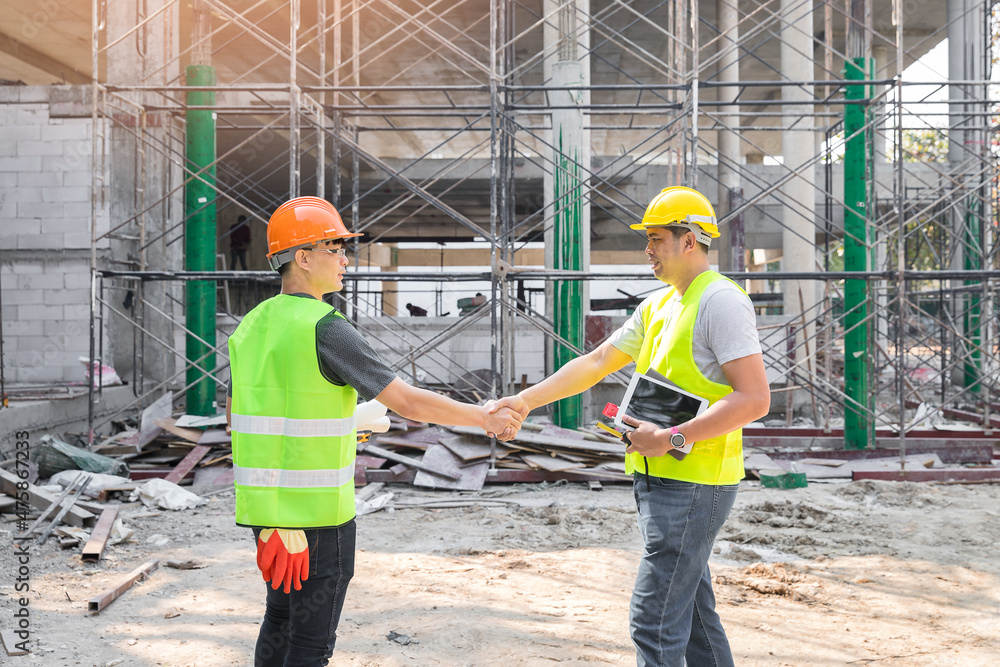 Builders greeting each other with handshake on construction site ...