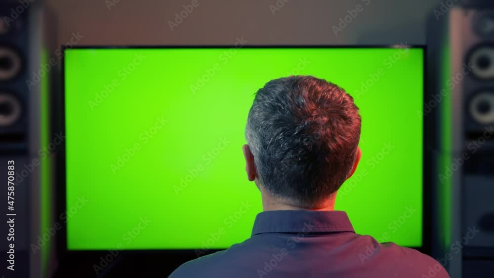 Man gesturing at a blank green screen of a TV or computer with his hand ...