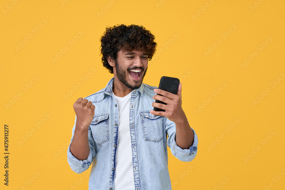 Excited happy young indian man winner feeling joy using smartphone ...