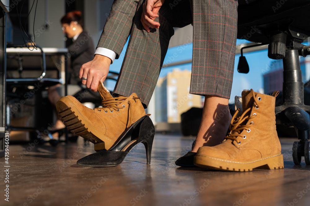 Business woman changes shoes with high heels on boots in the office ...