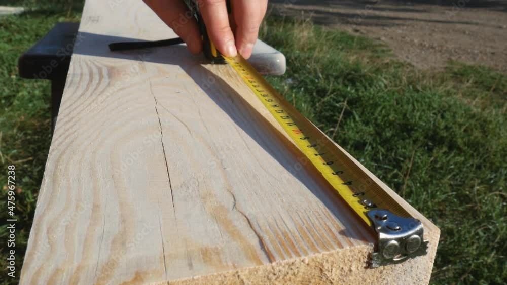 Using a ruler, the worker marks the dimensions with a pencil. Yellow ...