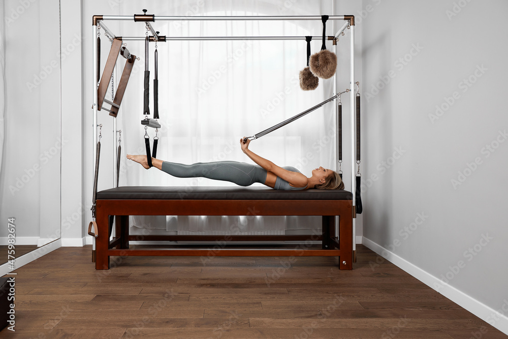 beautiful girl trains on the modern reformer simulator to work out deep ...