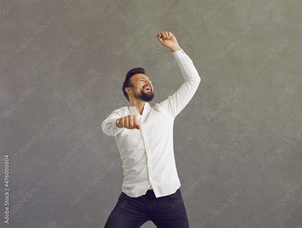 Happy cheerful handsome young man dancing gangnam style against grey ...