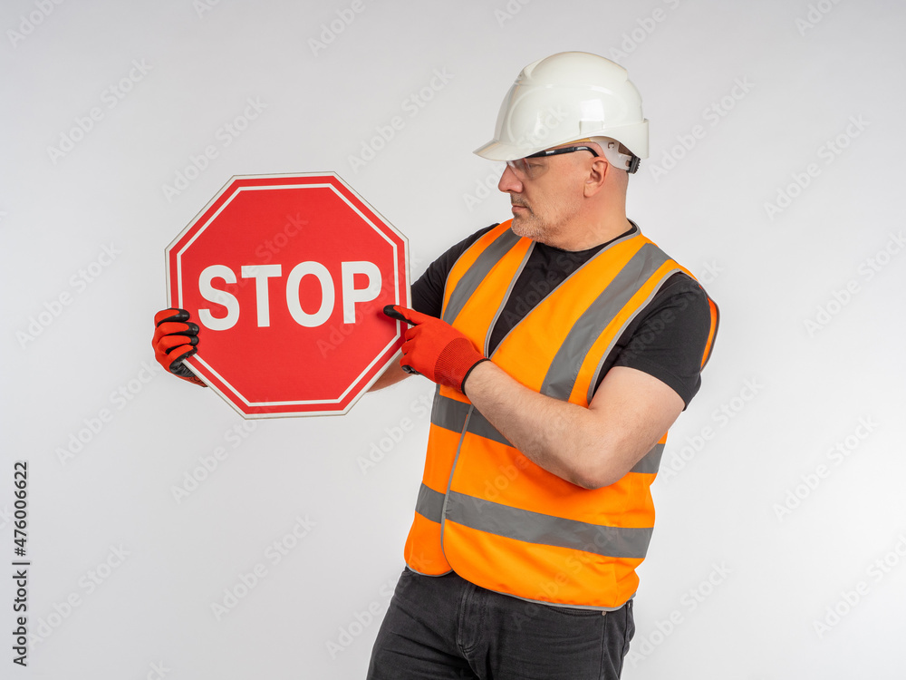 A builder with a stop sign in his hands. Red forbidding sign ...