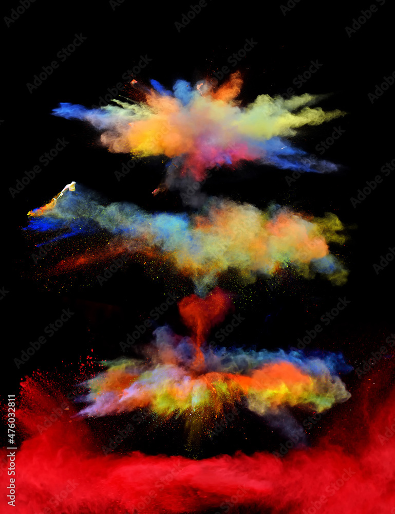 A vibrant colored powder paint cloud trio explodes in front of a black ...