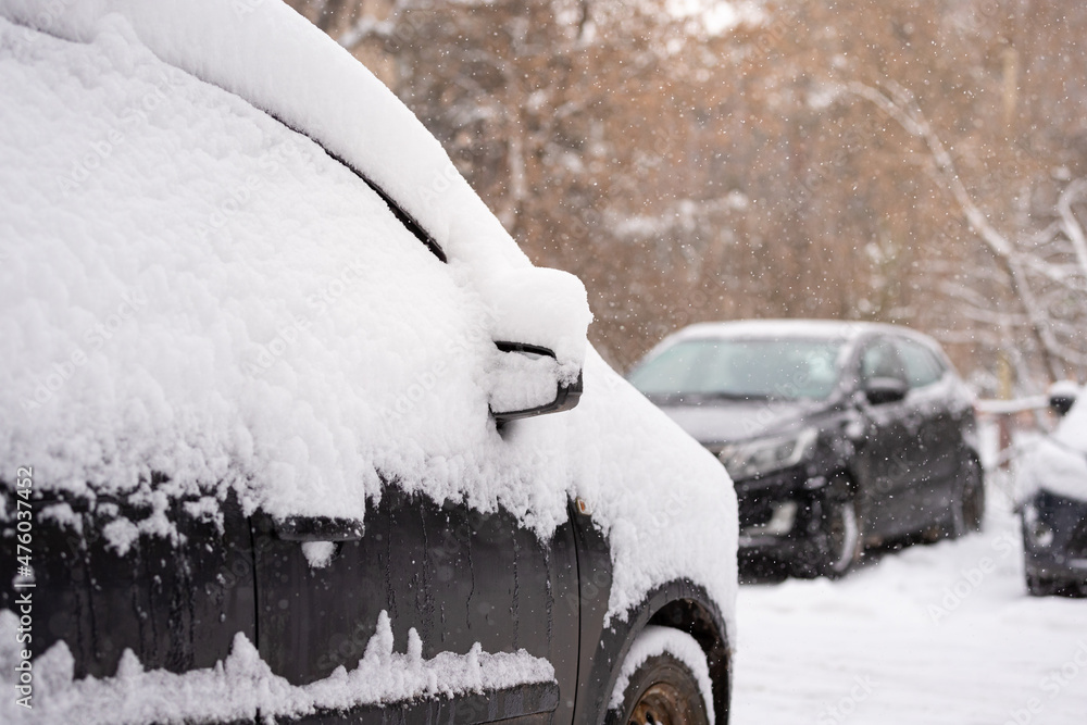 Heavy snowfall covered roads and cars. The car in the parking lot is ...