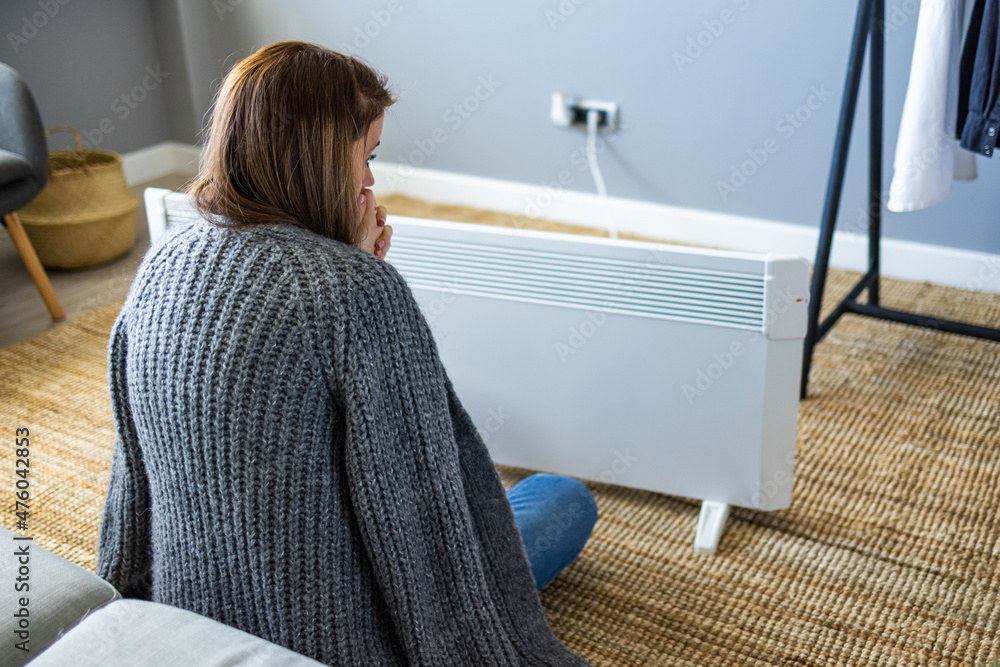 Foto de Cold home, freezing. Cold adult woman covered with clothes at ...