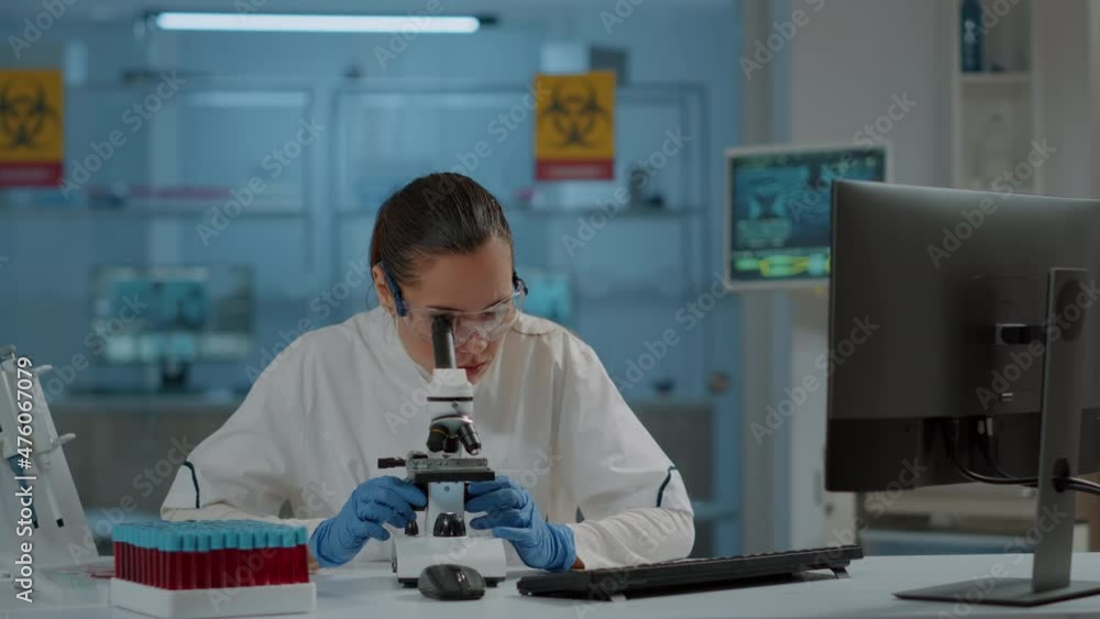 Lab worker using magnifying glass on microscope to work on science ...