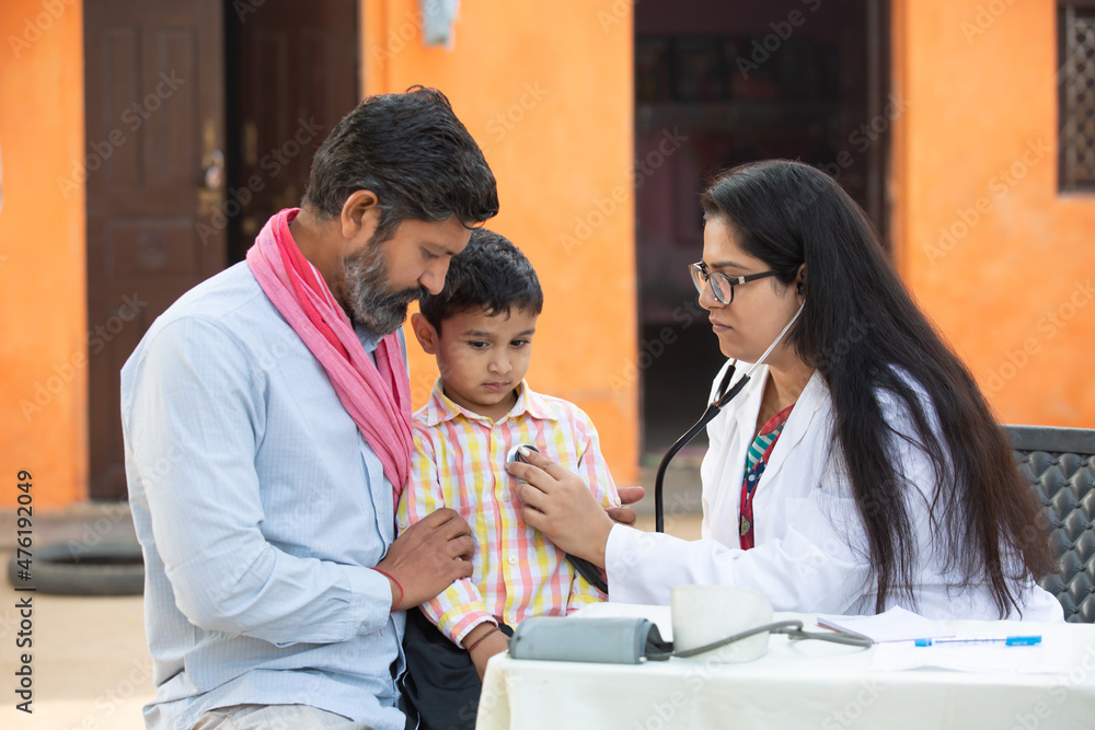 Foto de Indian female doctor with stethoscope checking little child ...