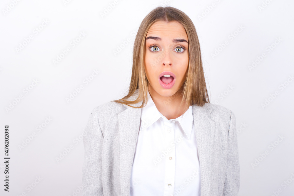 Shocked Young business woman wearing jacket over white background ...