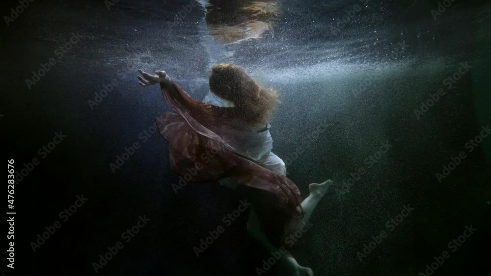beautiful lady is floating gracefully under water surface of swimming ...