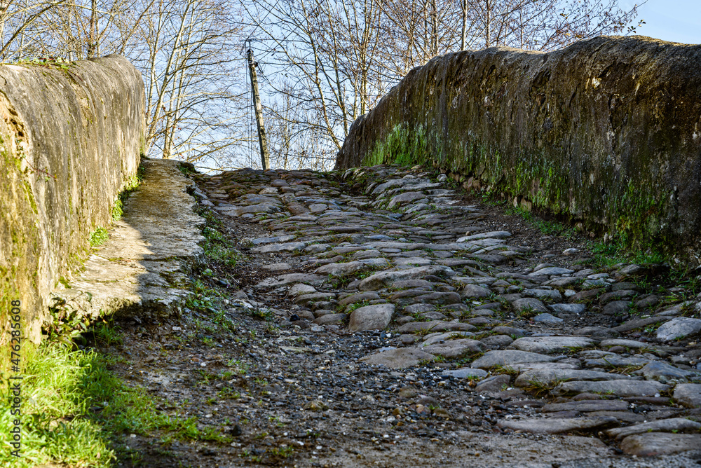 Stone path over the medieval bridge of the Camino de Santiago. Pebble ...