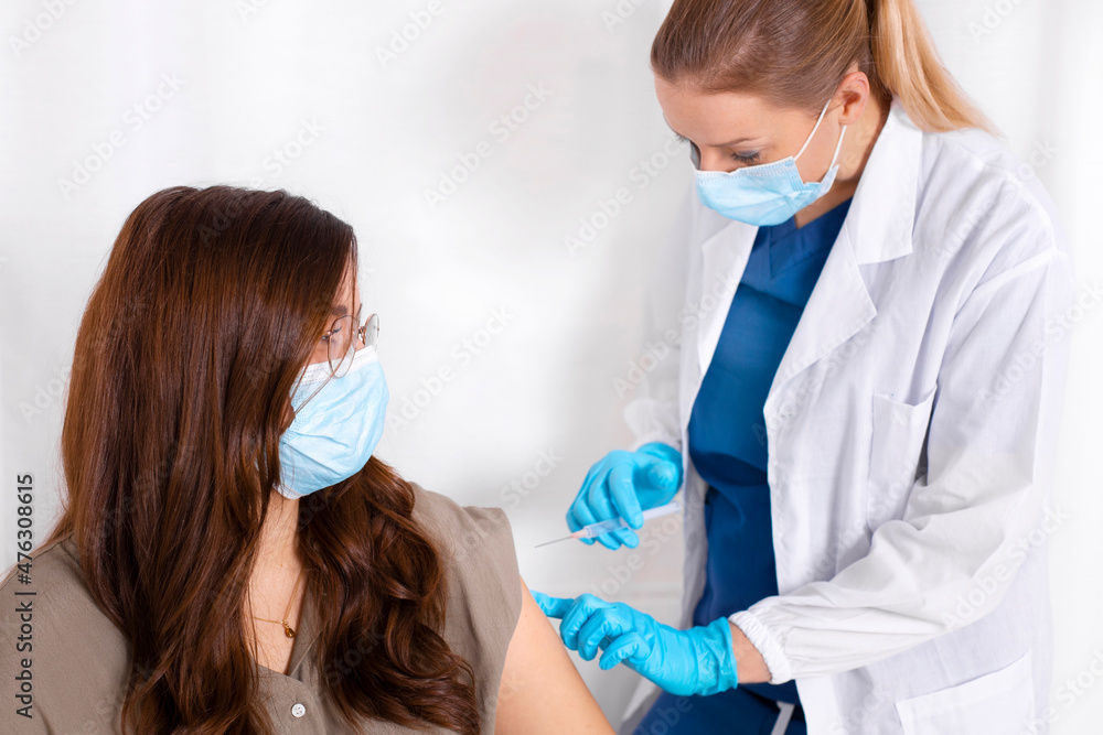 Covid 19 vaccine. Young brunette woman with medical face mask getting ...