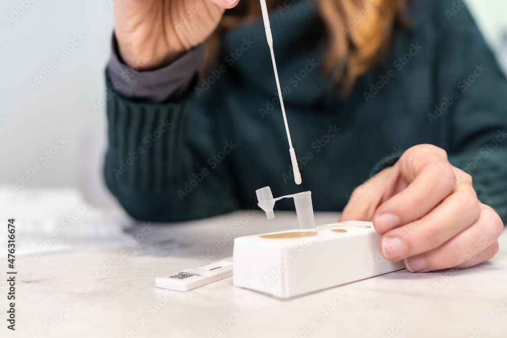 Putting the swab in the reagent liquid. A young woman doing the rapid ...