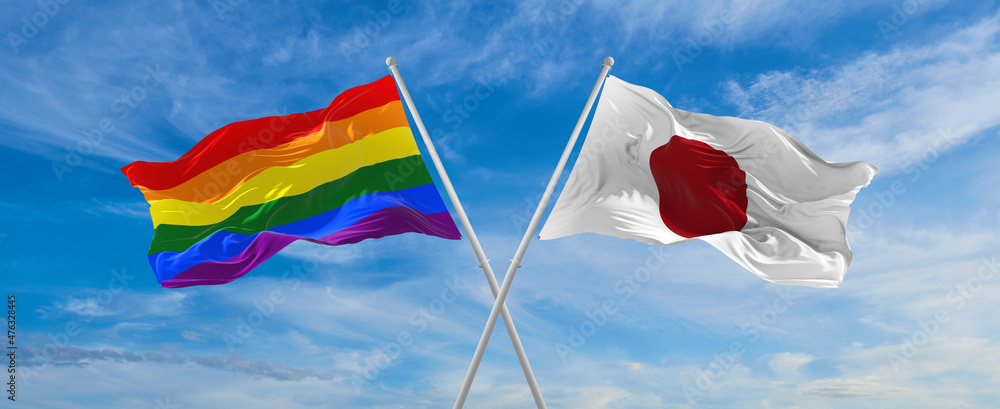 crossed flags of lgbt and japan flag waving in the wind at cloudy sky ...