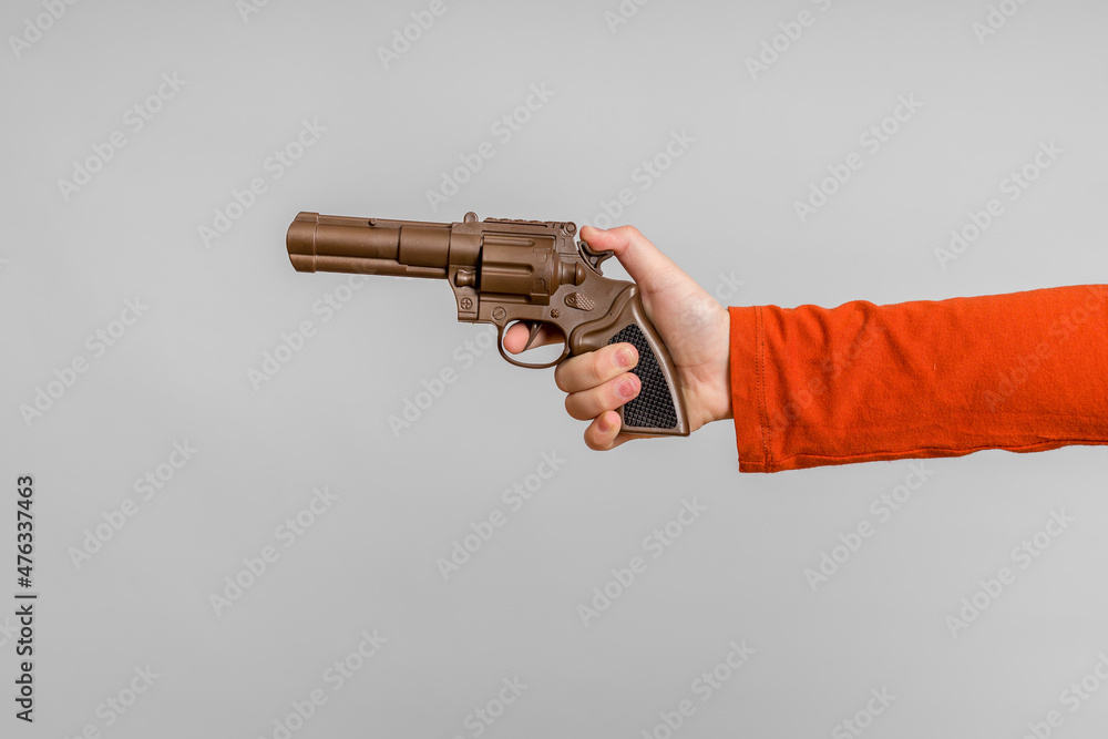toy gun in child's hand on gray background Stock Photo | Adobe Stock