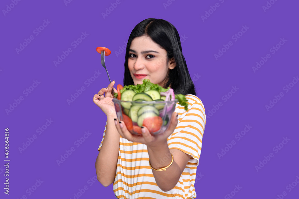 foodie girl holding vegetable salad bowl over purple background indain ...