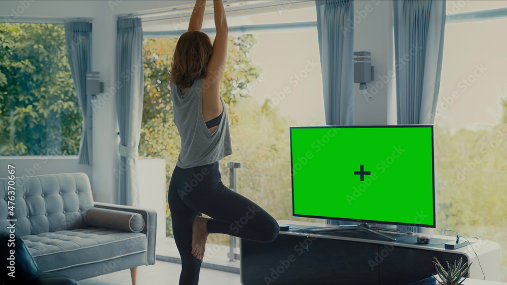 Girl stands in yoga pose infront of Green Screen mockup TV at home ...