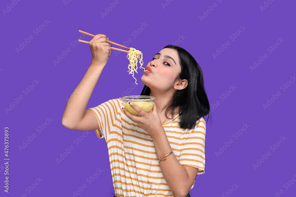 foodie girl eating noodle over purple background indian pakistani model ...