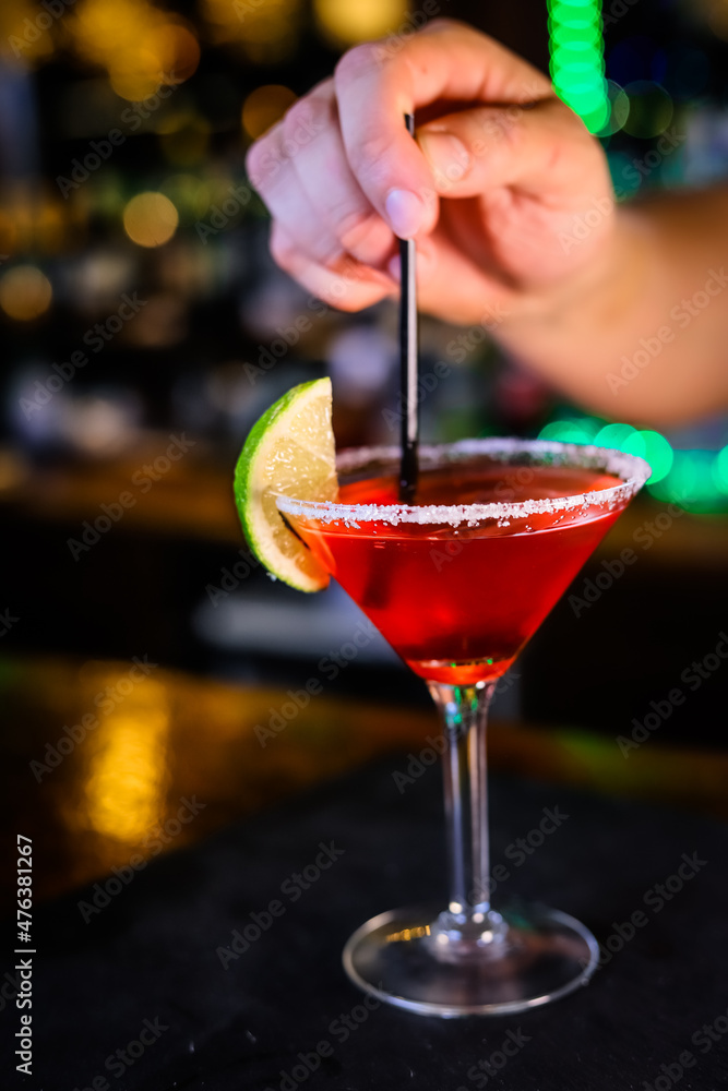 In a funnel-shaped glass on a long stem, a two-tone cocktail, dark red ...
