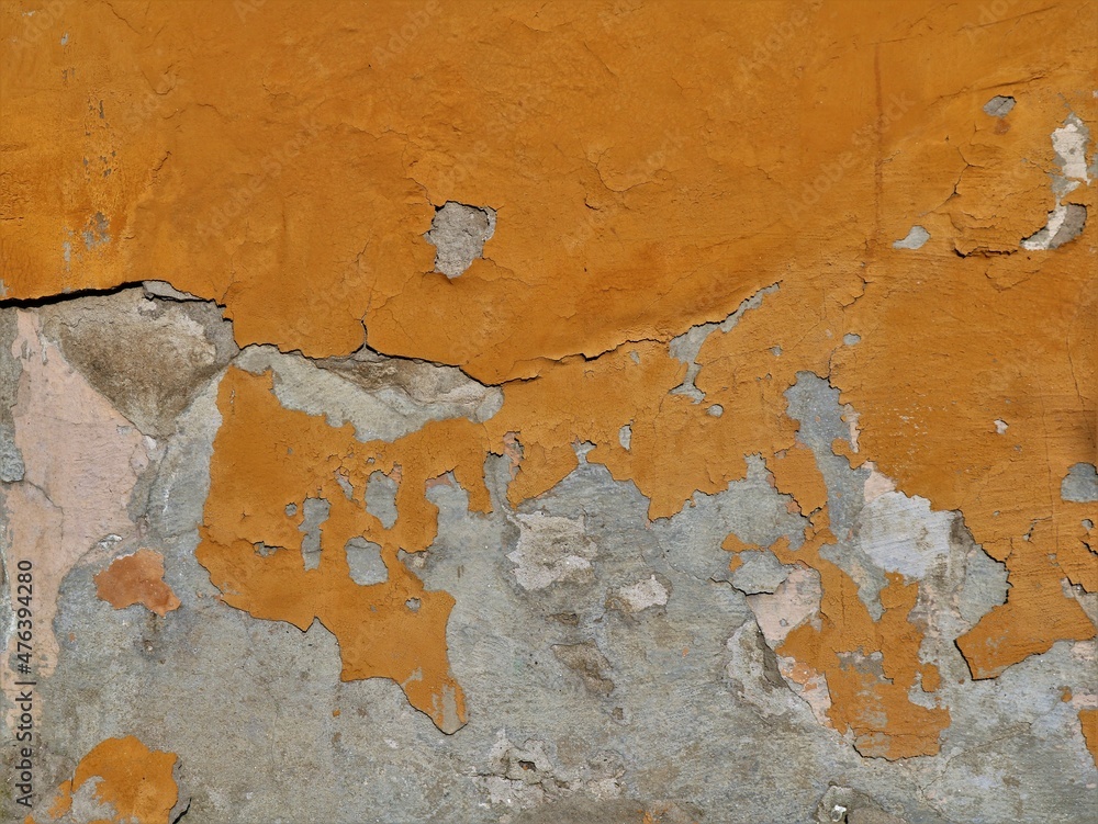 dilapidated concrete wall of building with peeling layer of brown paint ...