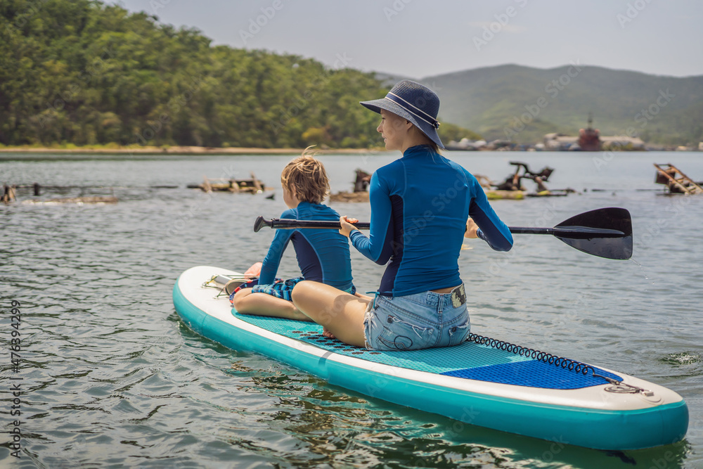 happy family of two, mother and son, enjoying stand up paddling during ...
