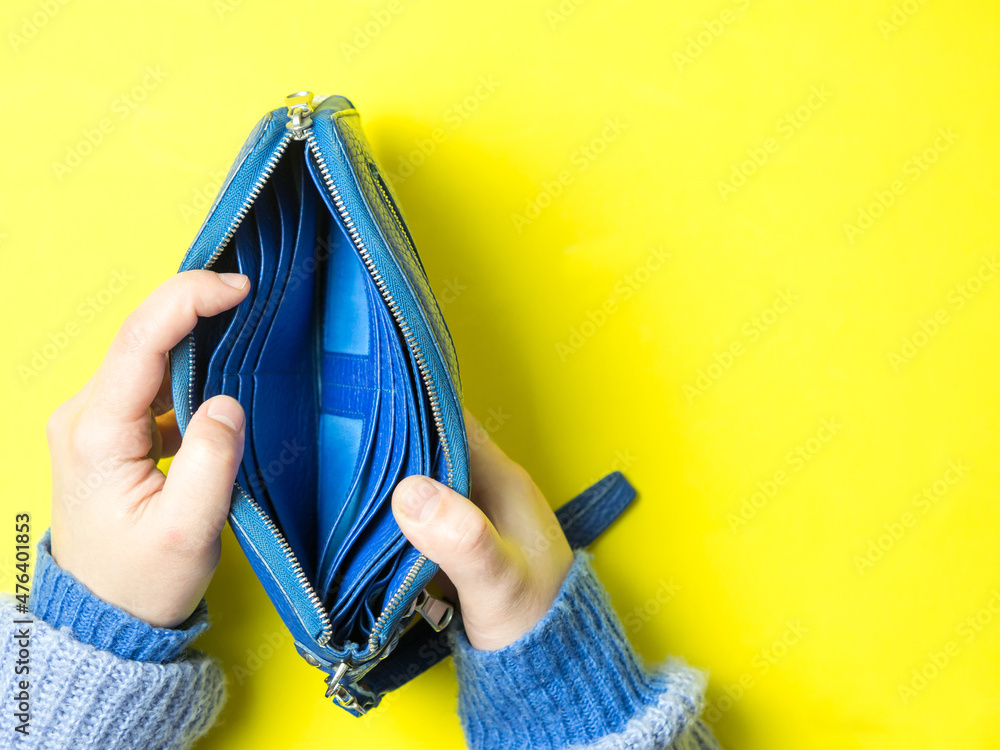 girl opens empty wallet on yellow background, concept of poverty and no ...