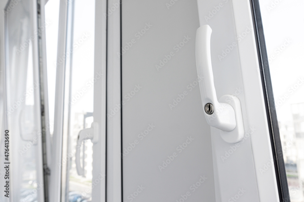 Opened white plastic window handle in upright position close-up. New ...