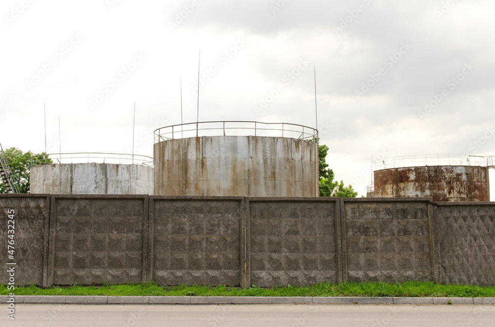 Old dirty oil storage tanks behind the concrete fence Stock Photo ...