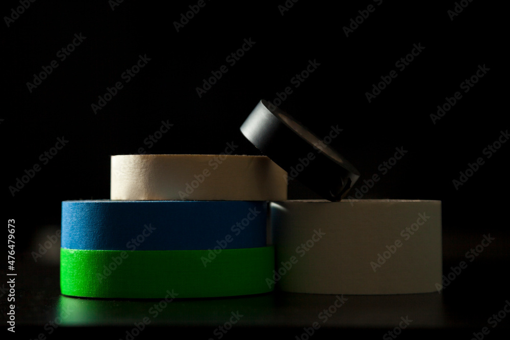 Colored adhesive tapes stacked on a table and black background. With ...