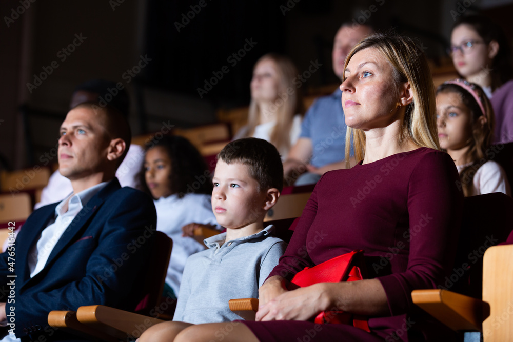 Young parents visiting theater with their tween son, consumed with ...