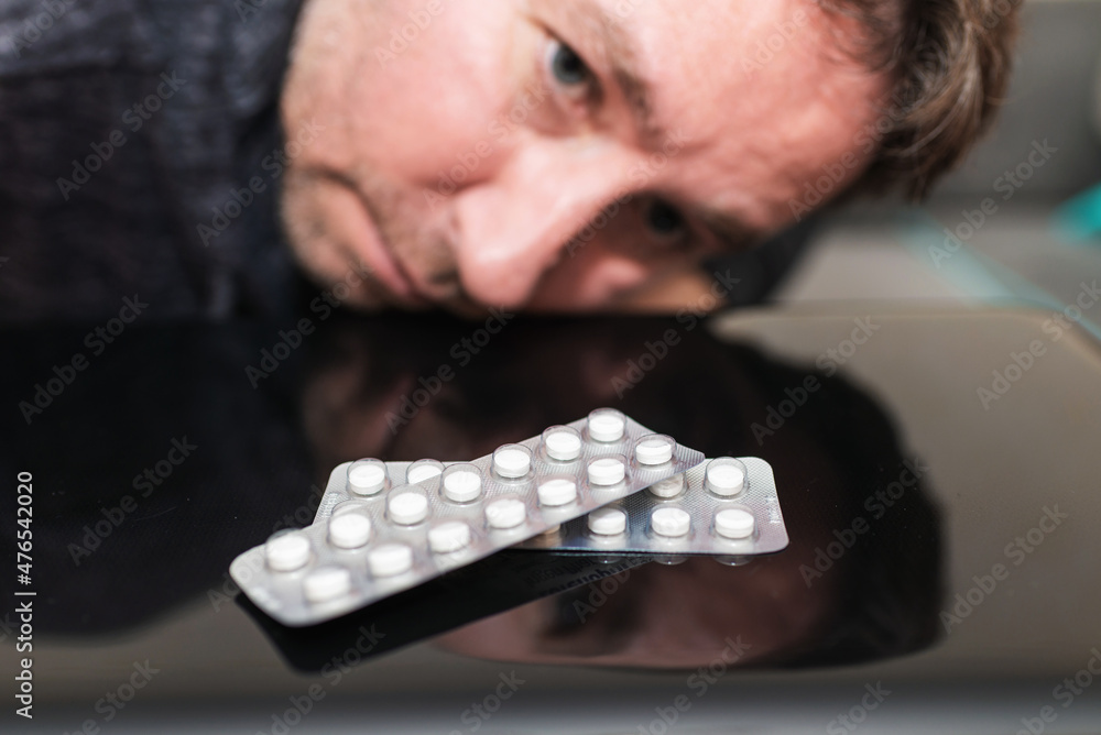 Narcotic addict white medicine pills on black table with reflection.The ...