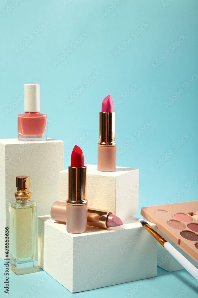 Different luxury makeup products on a white geometric podium on blue ...