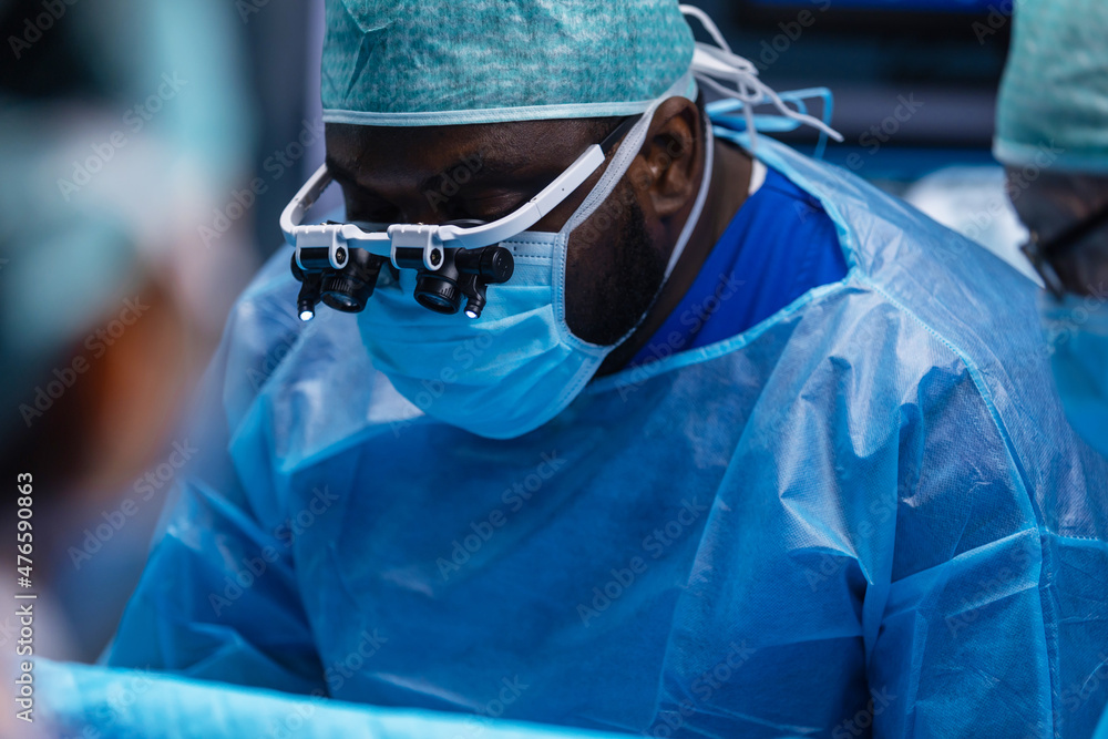 Multiracial team of professional medical surgeons performs the surgical ...