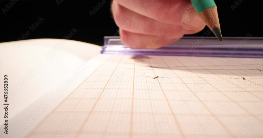 Drawing a pencil line on the ruler on the drawing sheet. Close-up of ...