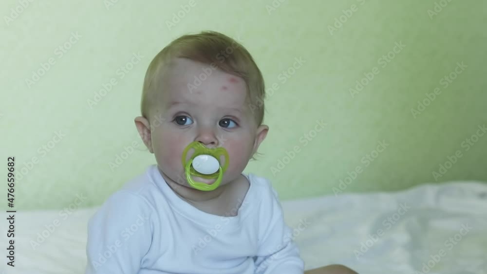Defocused face of cute funny baby with blue eyes posing with a pacifier ...