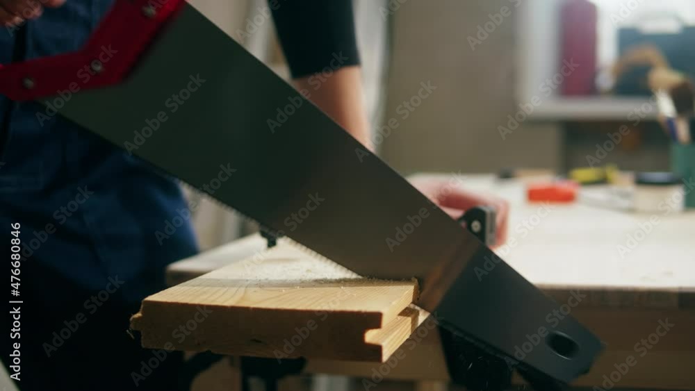 Woman builder sawing wooden board close-up. Female carpenter cutting ...
