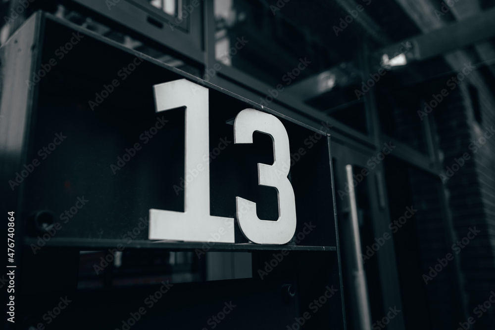House number thirteen 13 on a black brick wall. High resolution with ...
