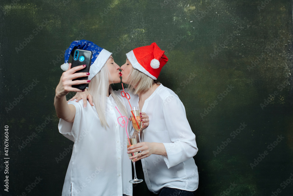 two girlfriends kissing on the lips in bright santa hats, having fun ...