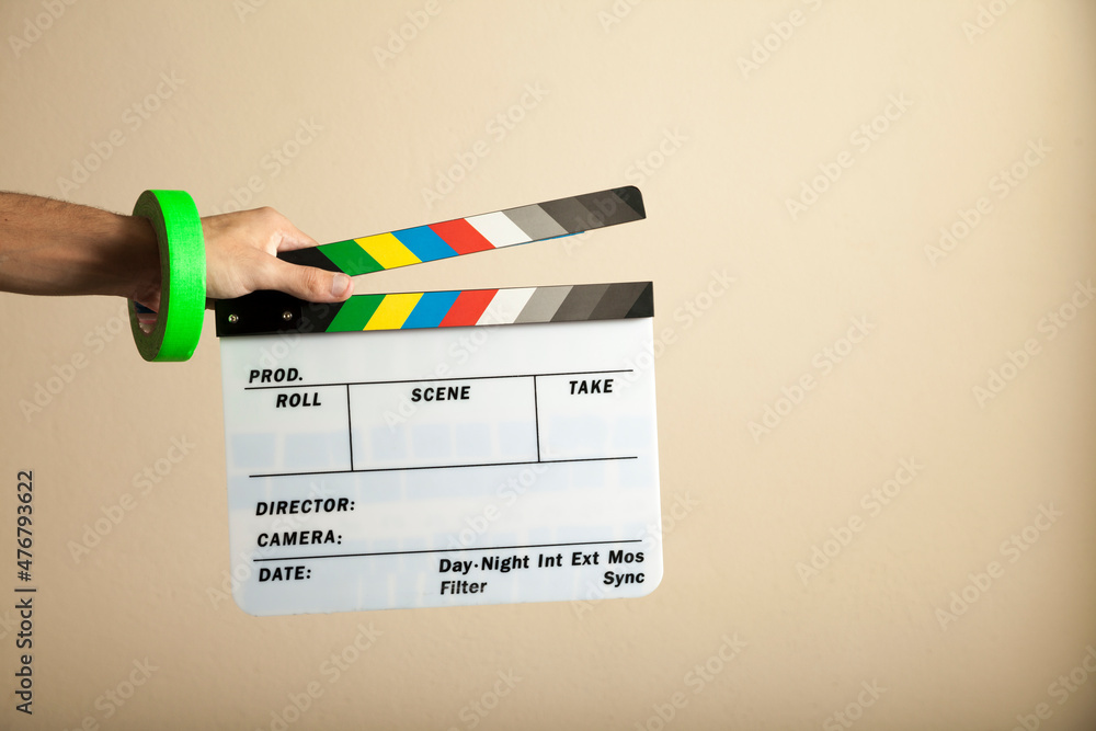 A hand holding clapperboard with a production tape on the wrist ...