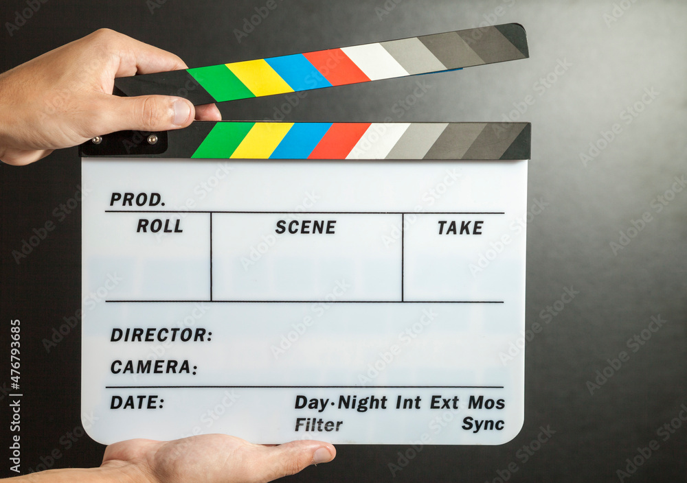 Man holding movie clapper board on black recording studio background ...