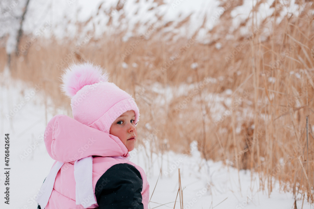 Closeup photo of female Russian kid with back to camera sitting in snow ...